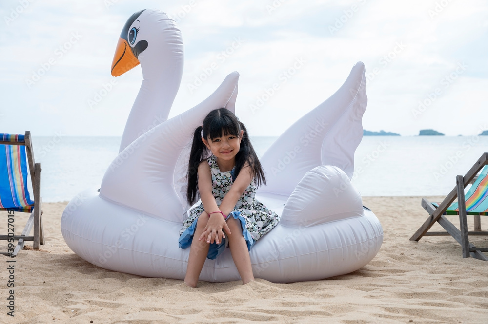 Happy Asian girl kid sitting on swan Floating raft on sand beach summer ...
