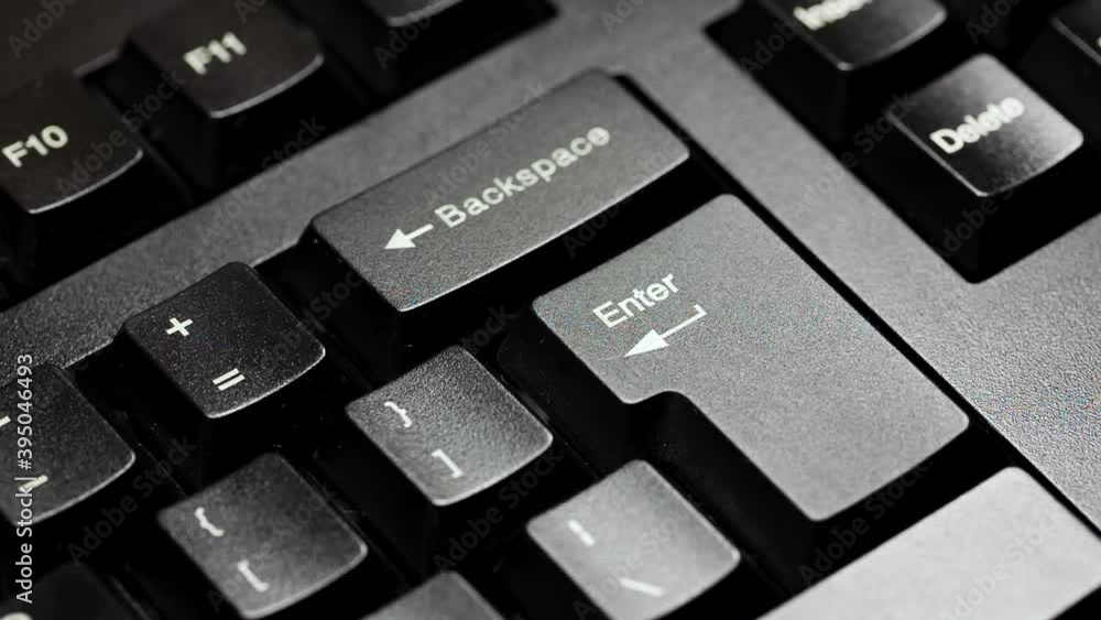 Finger presses the enter key on a modern black desktop pc keyboard ...