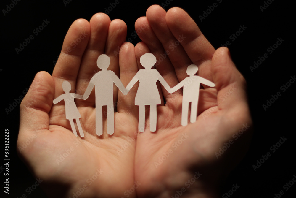 A cut out paper family holding hands, forming a chain, with cupped ...