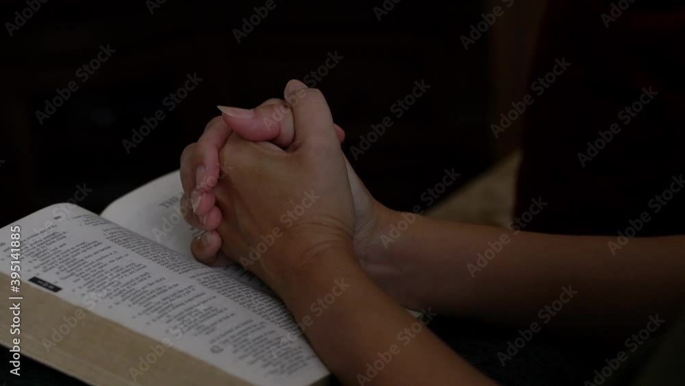 Woman hands on top of holy bible, clasping together in prayer position ...