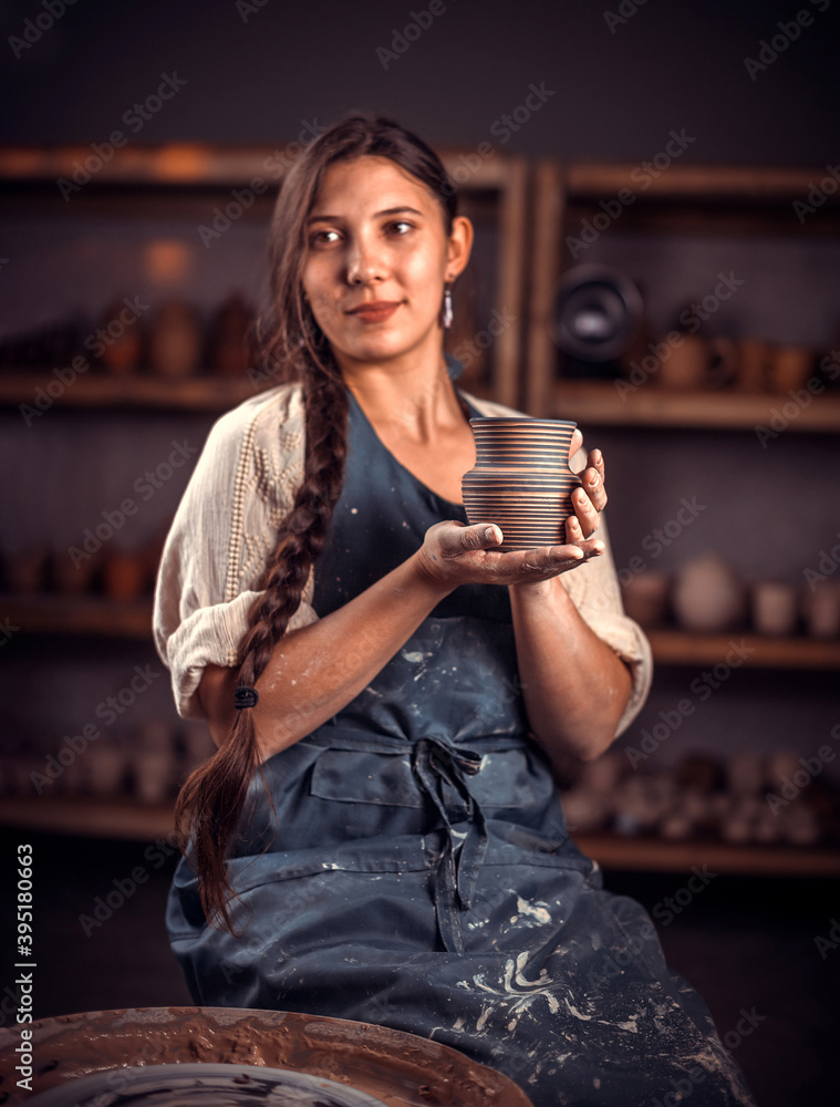 Pottery girl shows the finished clay product in the pottery workshop ...