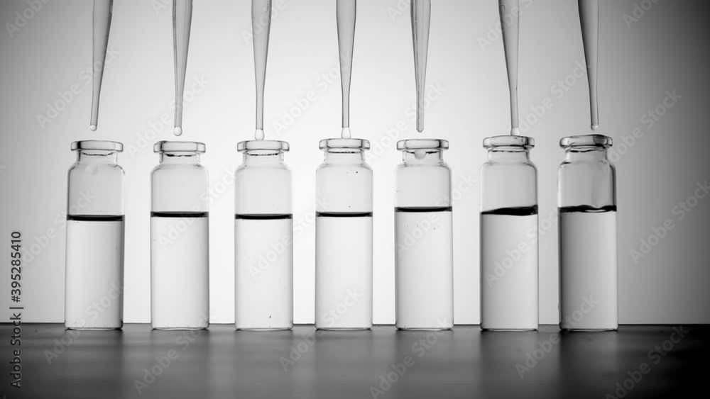 Drops fall from a pipette into a row of vials. Making a vaccine. Stock ...