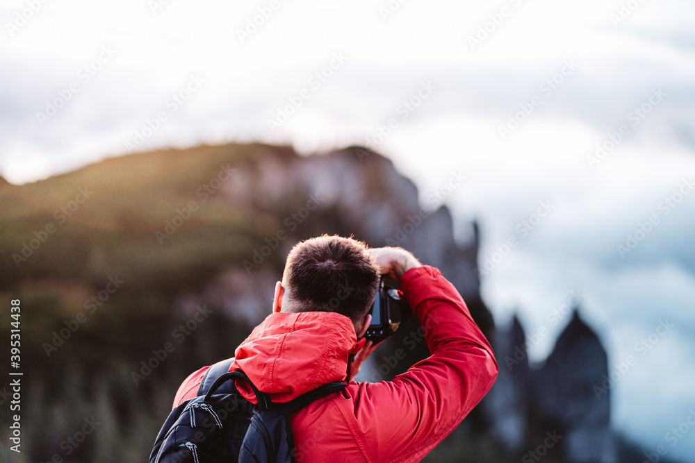 Back view of climber taking photos on top of the mountain cliff ...
