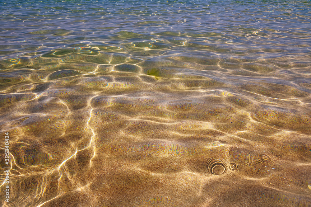 crystal clear sea water in shallow water with sun glare abstract ...