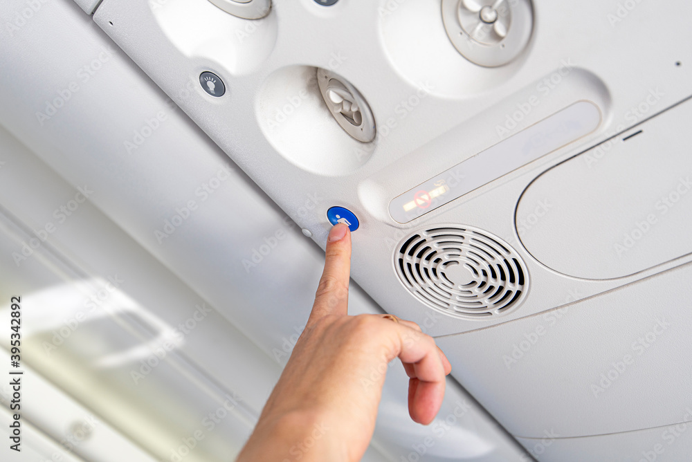 Passenger pressing the button to call cabin crew, stewardess for a ...
