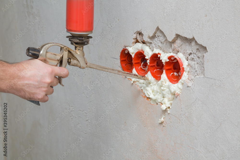 Zdjęcie Stock: Young adult man hand using spray gun and filling gap ...