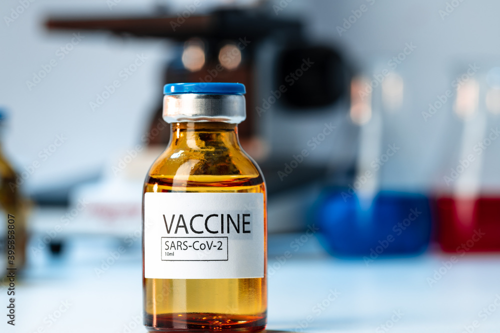 Vial of Covid-19 vaccine next to a microscope Stock Photo | Adobe Stock