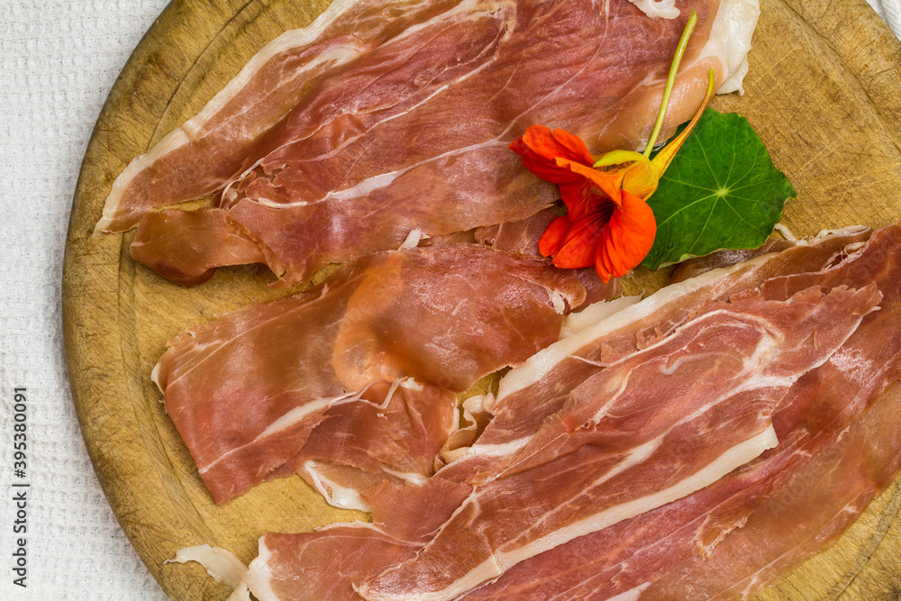 Crudo ham with caper flower on rustic wood board - top view image of ...