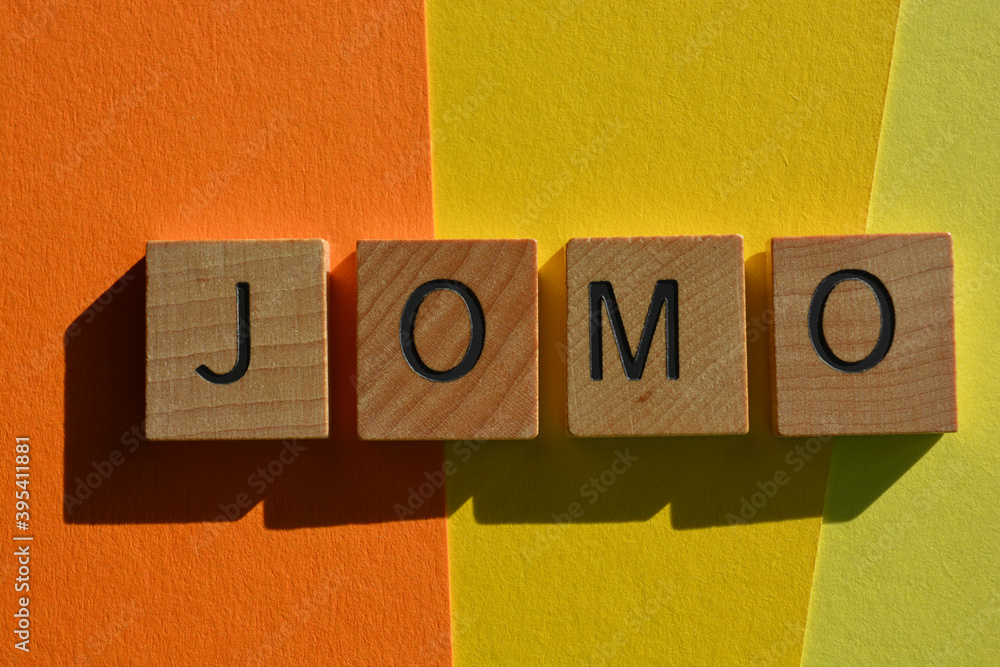 JOMO acronym for Joy of Missing Out, in wooden alphabet letters ...