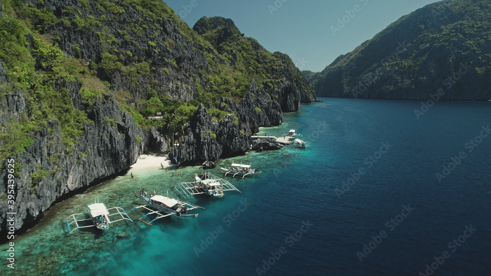Closeup aerial view of boats at ocean cliff coast with green tropical ...