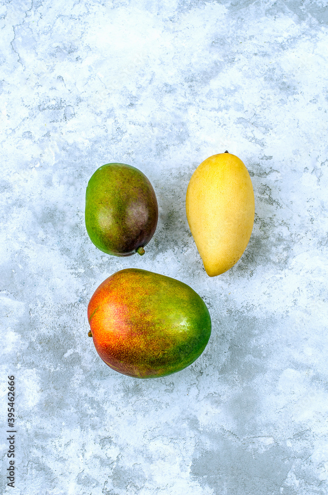 Three mangoes of different varieties, is laid out in a triangle on a ...