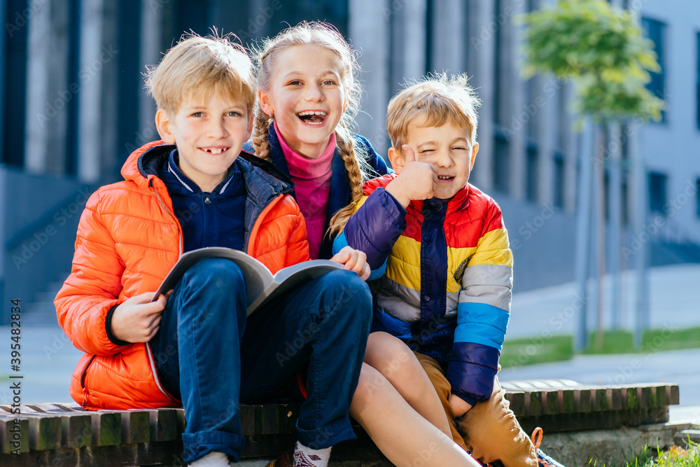 Group of three children reading from notebook all together. School kids ...
