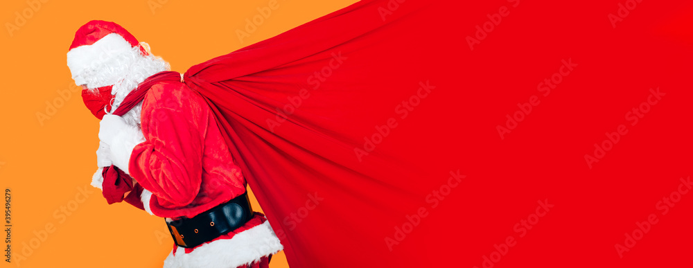 Santa Claus wearing a red face mask is pulling a huge bag of gifts that ...