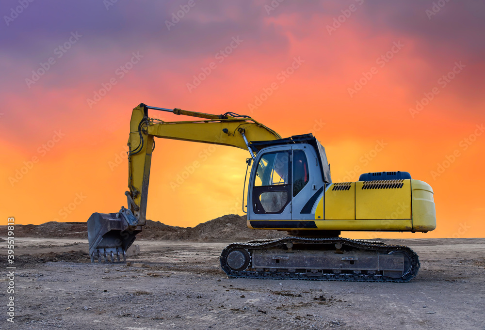 Excavator during earthmoving at construction site on sunset background ...