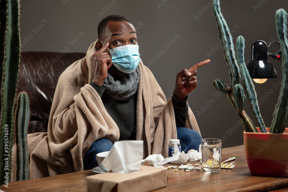 Protective face mask. Young man wrapped in a plaid looks sick, ill ...