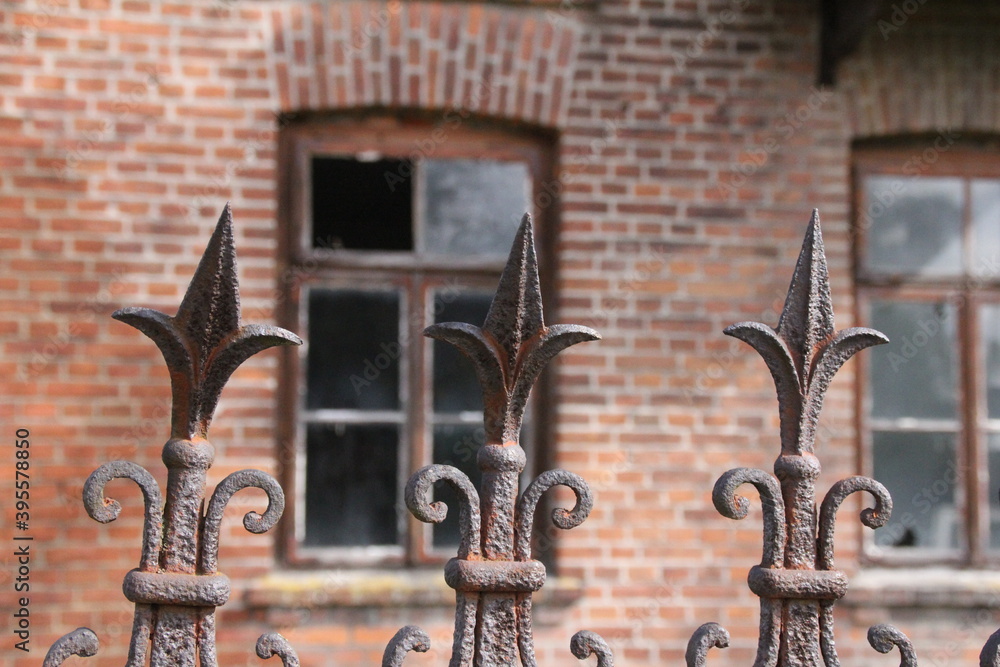 protruding pins of an old metal fence and behind them a blurred view of ...