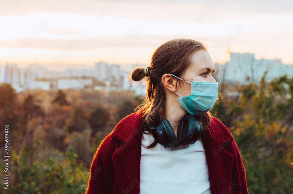 Side view of a woman wearing a face mask and headphones around neck ...