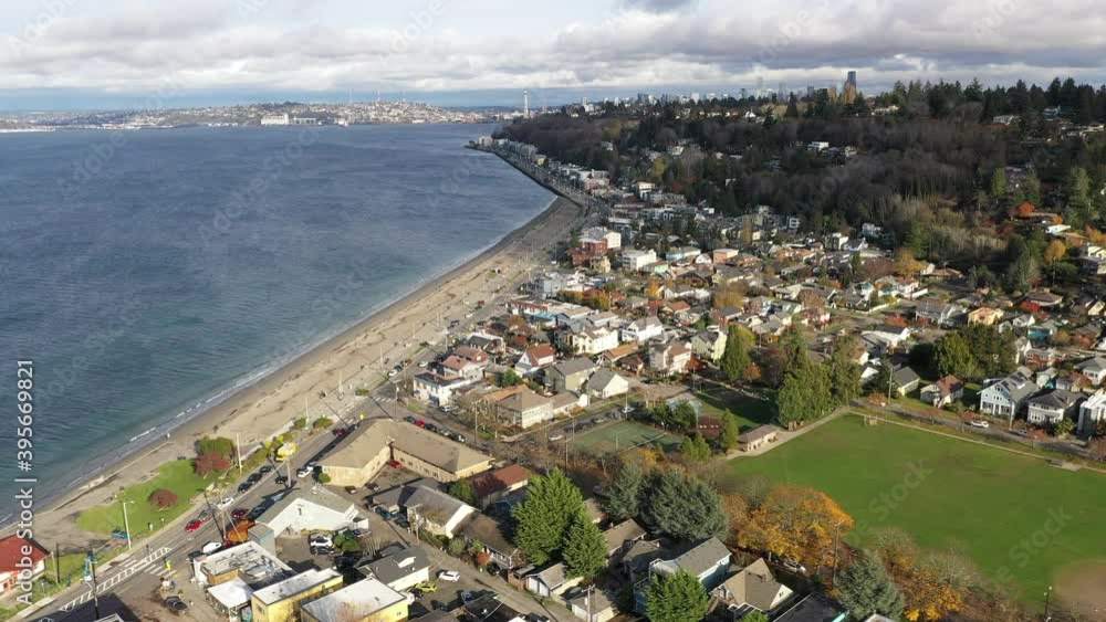 Aerial / drone orbiting footage of Alki Beach, sandy shoreline with a ...
