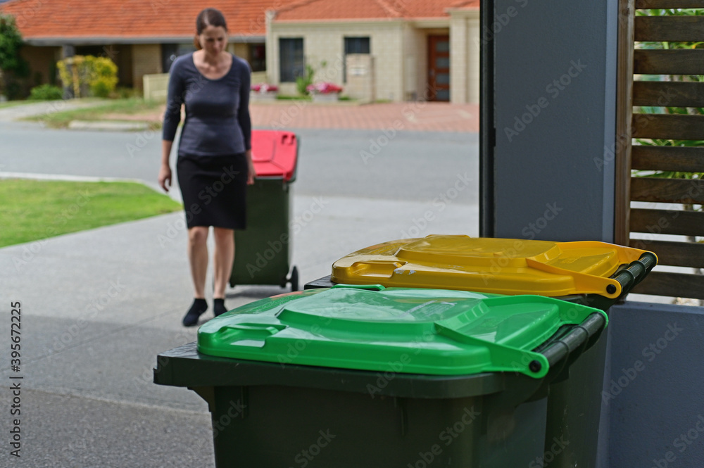 Adult woman collecting rubbish bin from road side on rubbish day Stock ...