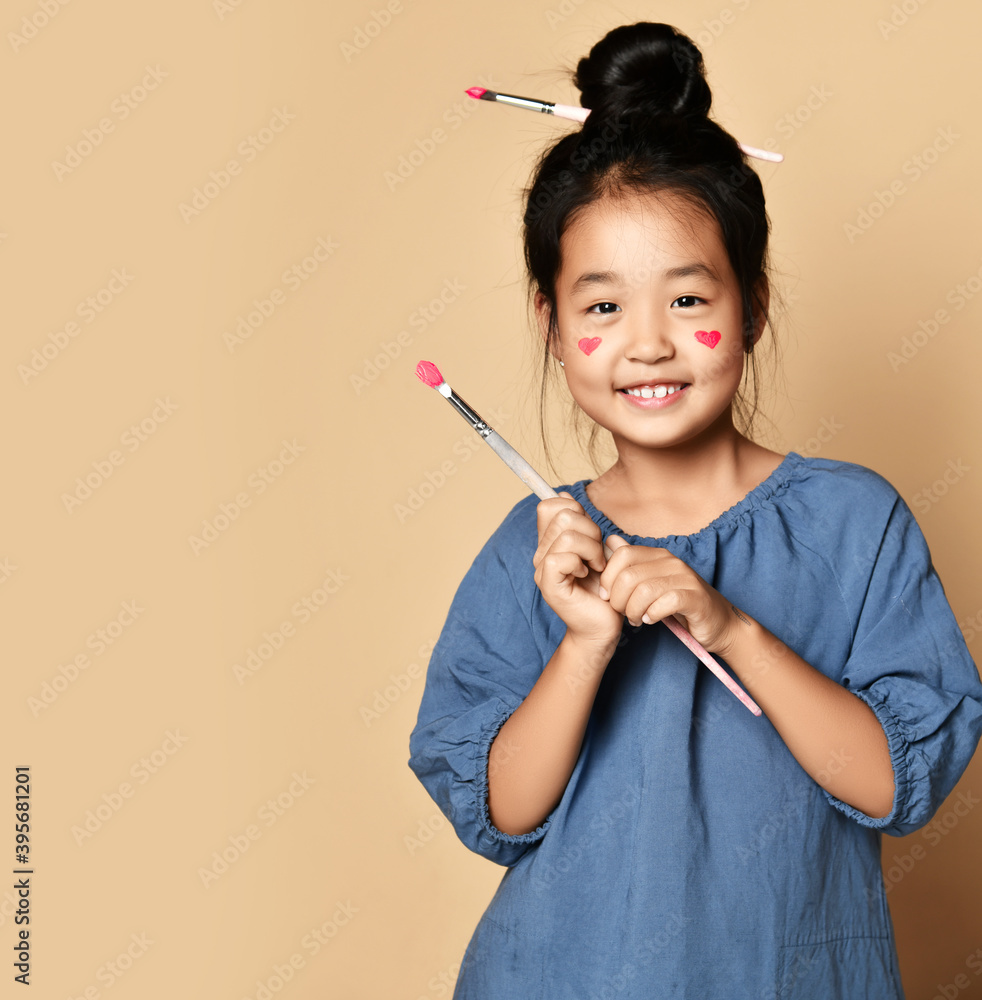Cute smiling asian kid girl artist with painted red hearts on cheeks ...