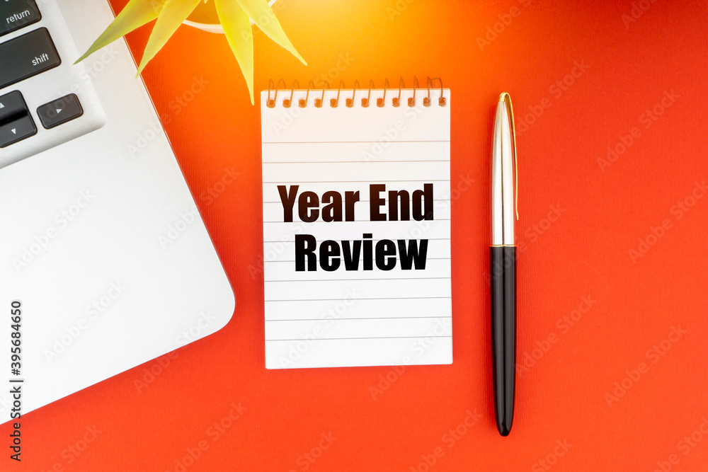 YEAR END REVIEW text with notepad, laptop, fountain pen and decorative ...