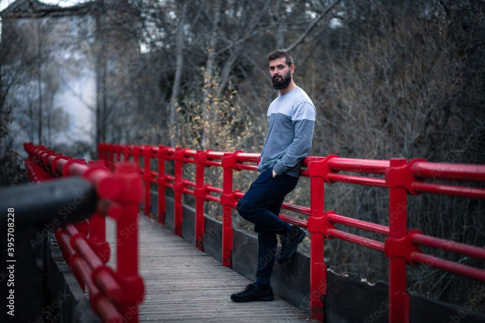 young handsome man leaning on the hand rail of a beautiful bridge with ...