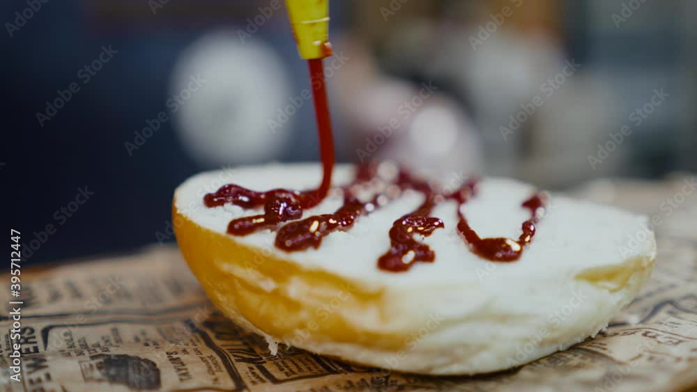 Chef preparing juicy burger and pours spicy tomato sauce on it making ...