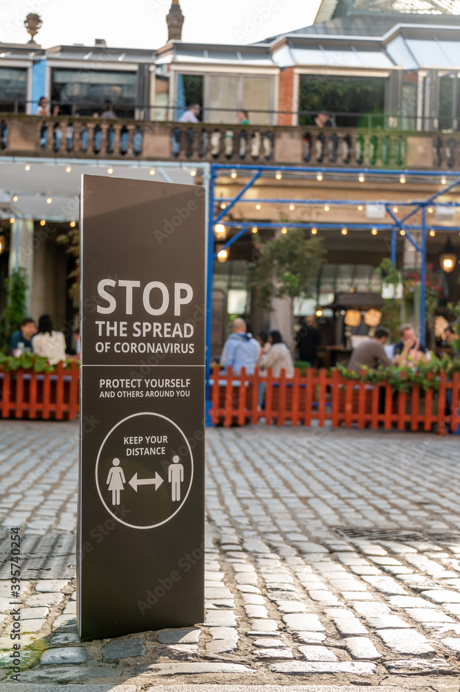 Covid 19 Social Distancing warning sign at Covent Garden with diners at ...