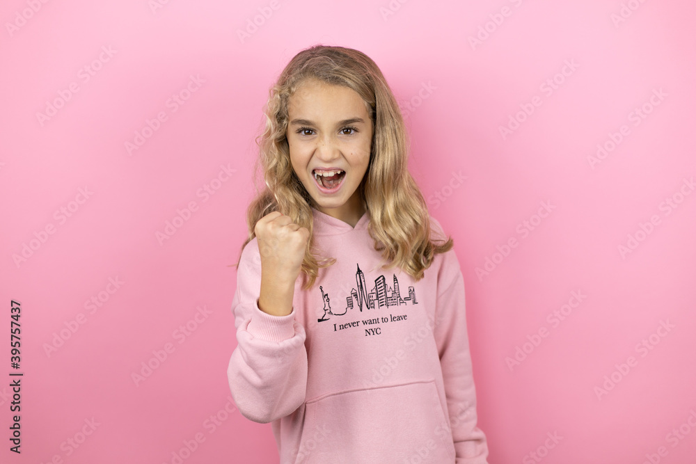 Young beautiful child girl standing over isolated pink background angry ...