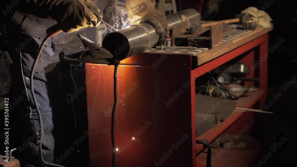 Welder welding stainless steel pipe together using shielded metal arc ...