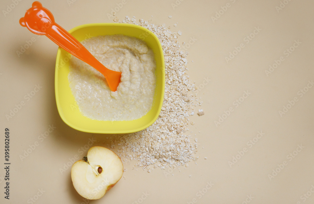 baby oatmeal puree in a bright light green silicone plate with a spoon ...