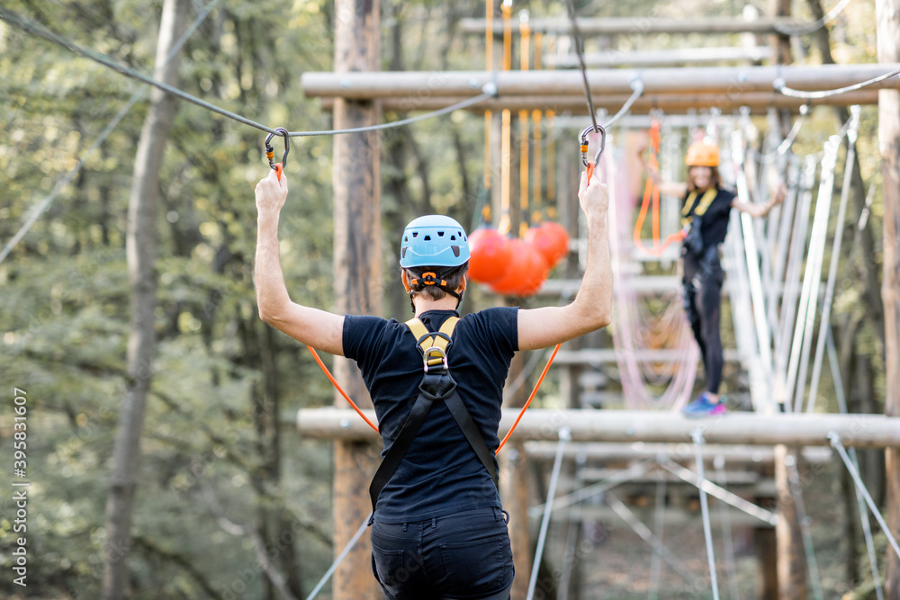 Well-equipped man and woman having an active recreation, climbing ropes ...