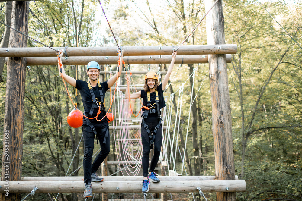 Well-equipped man and woman having an active recreation, climbing ropes ...