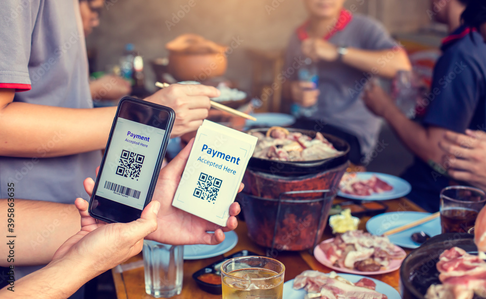 Hand holding smartphone to scan Qr code payment tag with blurry grilled ...