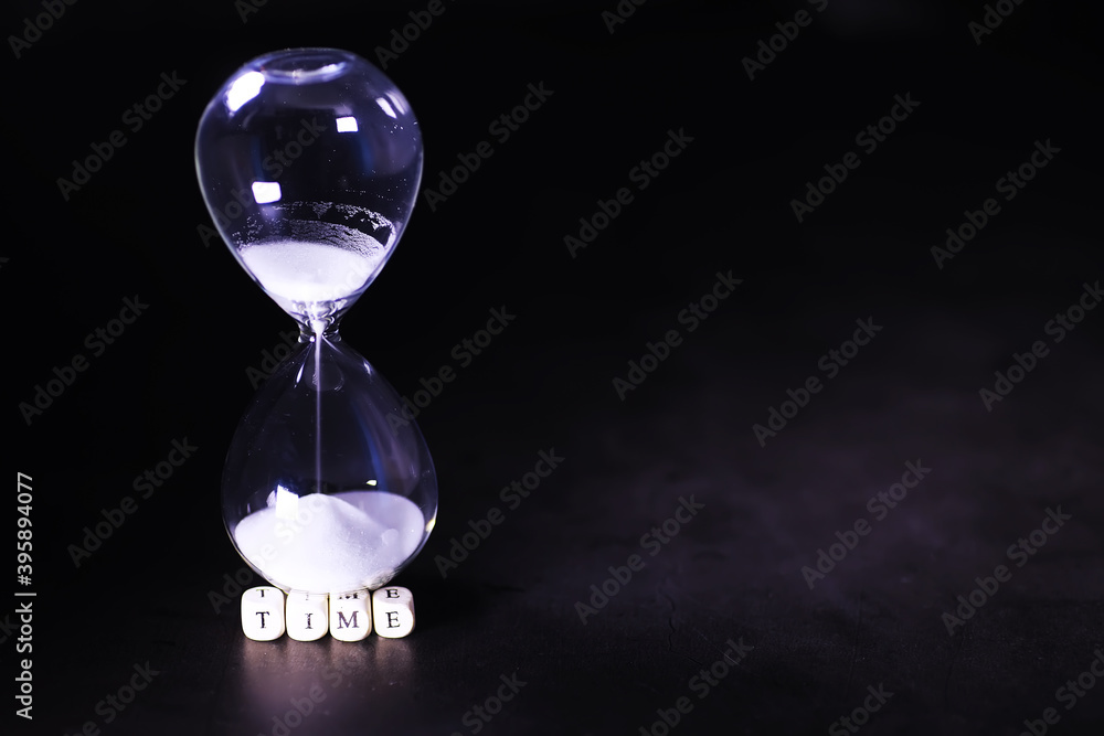 Sand running through the bulbs of an hourglass measuring the passing ...