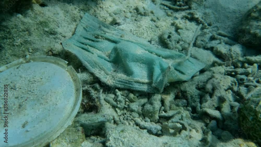 Face mask, plastic and other debris on seabed, tropical fish swim over ...