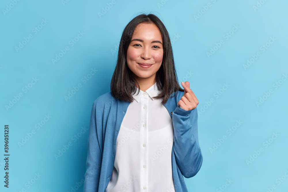 Lovely brunette Asian woman with rouge cheeks show mini heart gesture ...