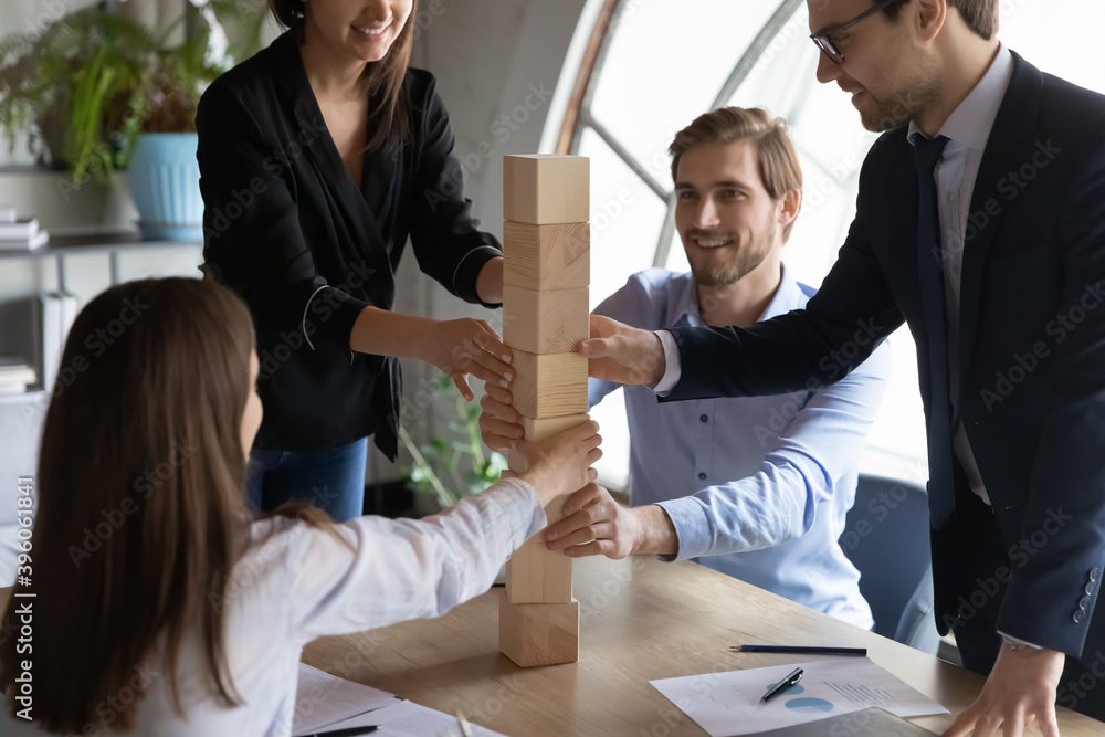 Smiling friendly diverse young staff engaged in building tower of ...