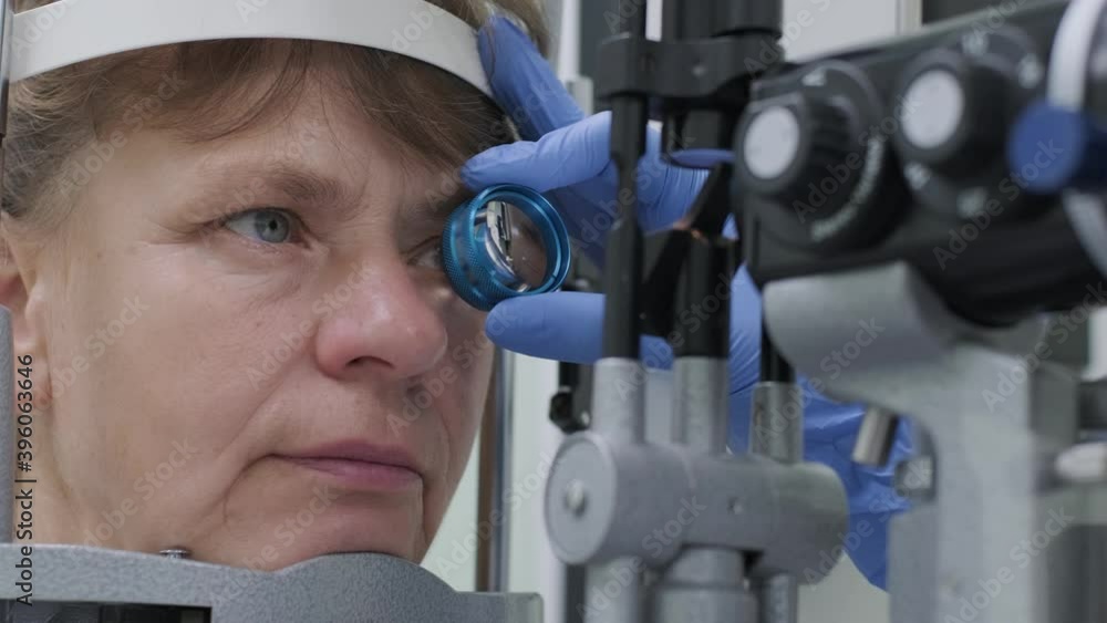Woman doctor is viewing through ophthalmoscope in eyes of patient in ...