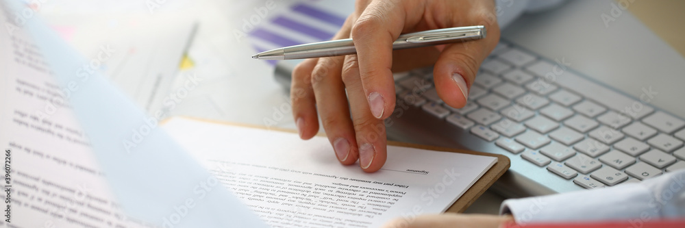 Confident office worker sitting at his workplace and reading agreement ...