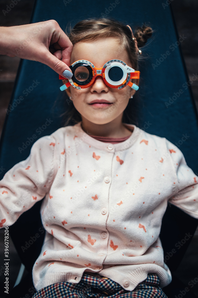 Beautiful and adorable little girl with optometry glasses receiving ...