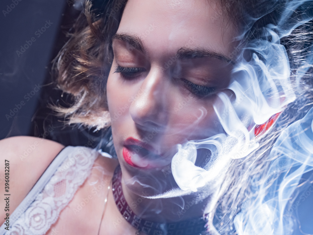 Face of a smoking girl close up. Smoke from a smoking cigarette next to ...