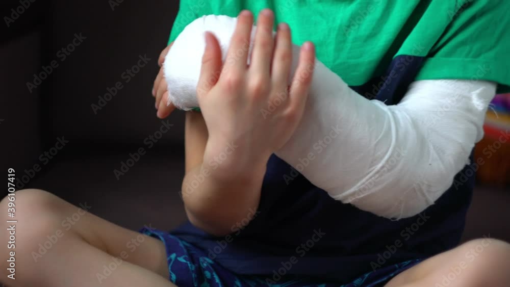 little boy lies on the bed with a fractured limb. a child's arm is ...