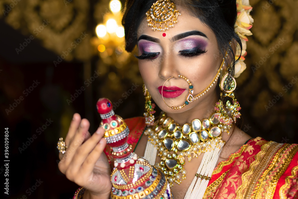 Portrait of very beautiful Indian bride holding traditional wooden ...