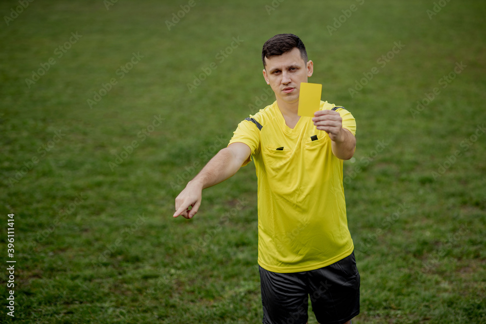 Angry football referee showing a yellow card and pointing with his hand ...