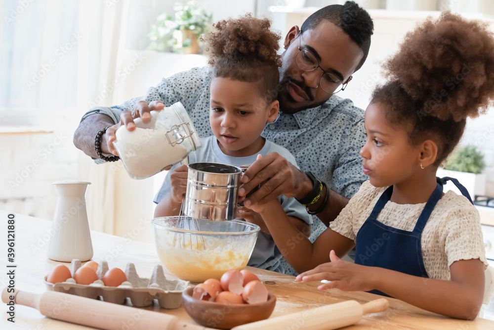 Cooking with daddy. Caring concentrated african foster father teaching ...