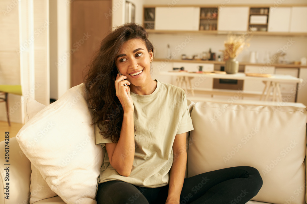 Technology, leisure, connection and communication. Cute young Latin female with voluminous hair ...