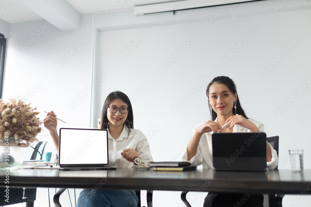 Portraits of two female office workers talking to each other while ...