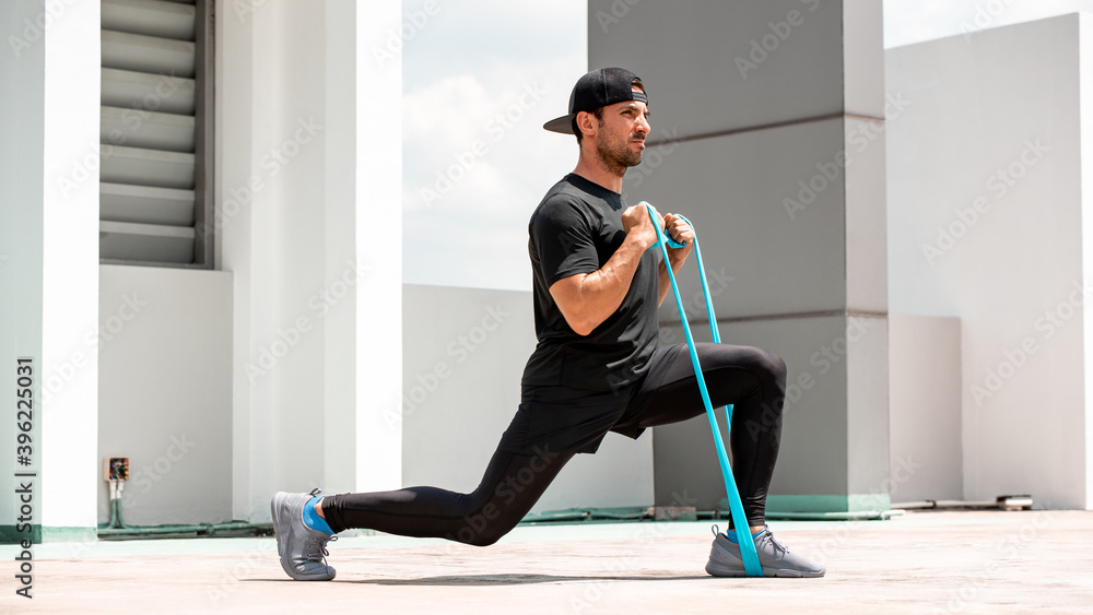 Handsome Latino sports man doing lunge workout with resitance band ...