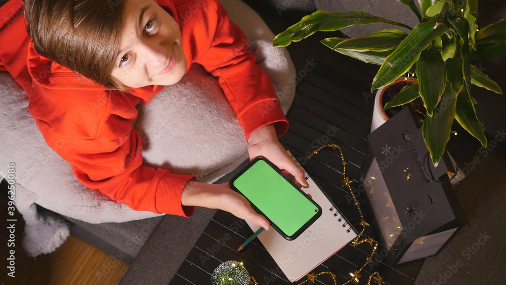 Teenager cute boy holding phone with green screen and looking at camera ...